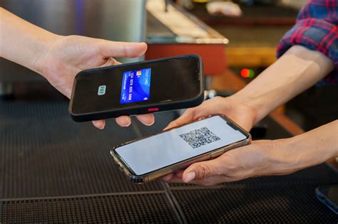 결제 계좌용 Qr코드로 전화기에 서 있는 베이커리 직원 송금 결제를 원하는 고객 고객은 Qr 코드를 스캔하여 휴대폰을 넘겨 신용
