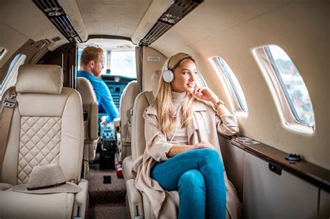 개인 제트기에 앉아 헤드폰을 통해 음악을 듣고 젊은 성공적인 여성 그녀는 시간을 확인 비즈니스 제트기에 대한 스톡 사진 및 기타 이미지 비즈니스 제트기 파일럿 2명