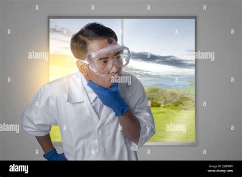 Asian Nerd Scientist Standing And Thinking Something With A Window Glass Background Stock Photo