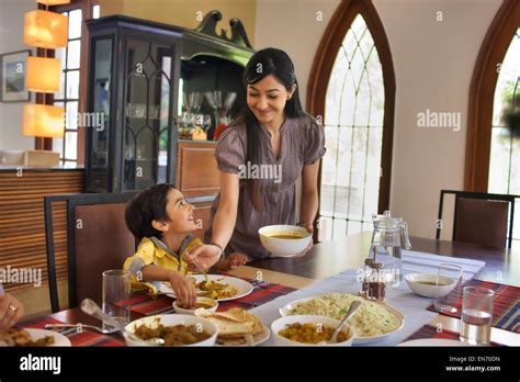 Mother serving food on sons plate Stock Photo - Alamy