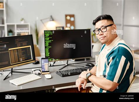 Portrait Of Asian It Developer Looking At Camera Against Programming