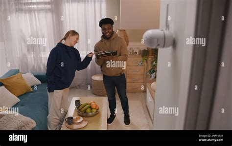 Multi Ethnic Couple Install And Set Up Security Camera Woman Moves To Check Motion Sensor On
