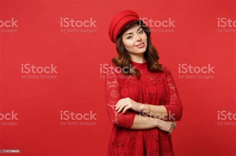 스튜디오에서 밝은 빨간색 배경에 고립 접힌 손을 잡고 카메라를 찾고 레이스 드레스와 모자에 아름 다운 젊은 여자의 초상화 사람들은 진심으로 감정 라이프 스타일 개념입니다