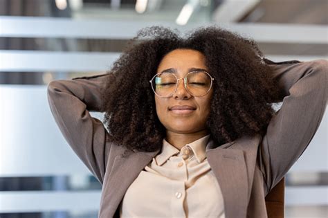 양복을 입은 아프리카계 미국인 젊은 사업가가 사무실 의자에 앉아 쉬고 있다 그녀는 두 손을 머리 뒤로 모으고 눈을 감았다 클로즈업 사진 일함에 대한 스톡 사진 및 기타
