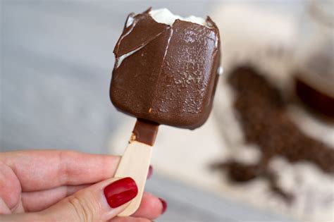 흐린 배경 매니큐어를 가진 여자 손은 반쯤 먹은 아이스크림을 들고 유리 컵에 담긴 강한 블랙 커피 에스프레소 테이블 위에 놓인 커피 냅킨에 긴 숟가락과 커피 원두 여름 다과