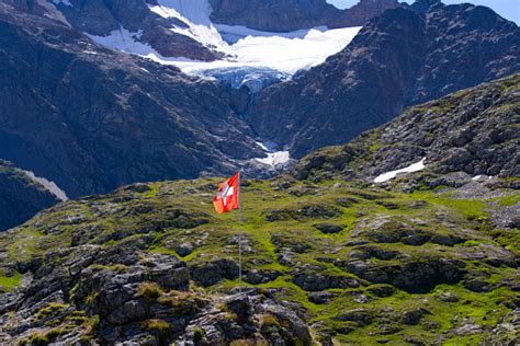 화창한 여름날 배경에 Tschingelfirn 빙하와 함께 스위스 산 패스 서스텐에서 흔들리는 스위스 국기 0명에 대한 스톡