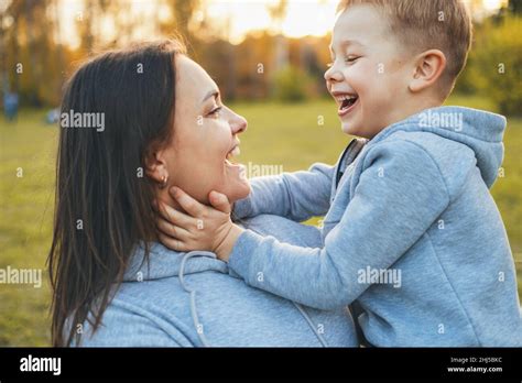 Side View Portrait Of A Boy Looking Into His Mother S Eyes While Playing With His Hands Touching