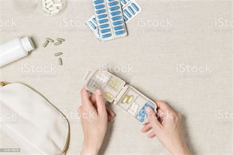 여성 손에 오픈 베이지 색 플라스틱 용기에 캡슐과 정제를 볼 수 있습니다 섬유 테이블에 비타민과 의약품의 매일 섭취를위한 알약 상자 아름다움과 건강 의료를 위한 라이프스타일