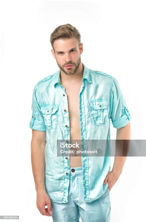 남자는 버튼없는 캐주얼 린넨 블루 셔츠에 매력적으로 보인다 차분한 얼굴에 남자는 주머니 흰색 배경에 손으로 자신있게 포즈를 취합니다 강모를 가진 남자는 캐주얼 또는 정장