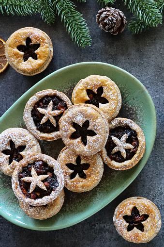 녹색 접시에 집에서 만든 다진 파이의 이미지 축제 크리스마스 디저트 달콤한 다진 고기로 가득 바삭 한 패스트리 별 모양의 과자 소나무 콘 가문비 나무 바늘 회색 배경 높은