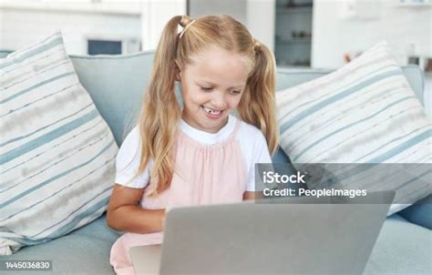 원격 학습 잠금 수업 또는 학습을 위해 집이나 집 거실의 소파에 있는 어린이 노트북 또는 교육 화상 통화 교실 지원을 위한 홈스쿨 기술에 대한 미소 행복한 소녀 또는 학생