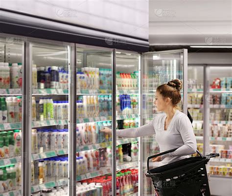 一位女士在超市的冰箱里挑选冷冻食品