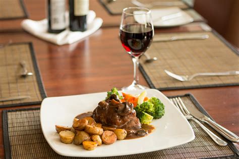 버섯 소스를 곁들인 소고기와 소금에 절인 감자 채소와 레드 와인 한 잔을 나무 테이블 위에 얹은 후 감자 요리에 대한 스톡 사진