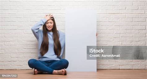 머리에 손으로 압박 하는 배너를 들고 벽돌 벽을 통해 젊은 중국 여자는 수치심과 깜짝 얼굴로 충격 분노와 좌절 두려워 하 고 실수에 대 한 화가 감정에 대한 스톡 사진 및