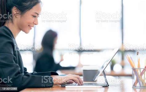 사무실 책상에 앉아 있는 동안 행복을 가지고 태블릿 컴퓨터에서 일하는 젊은 아시아 사업가의 클로즈업 샷 개념에 대한 스톡 사진