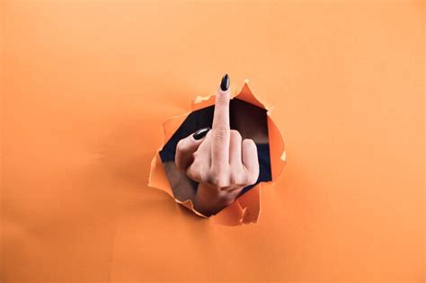 Женская рука показывает средний палец на оранжевом фоне Премиум фото