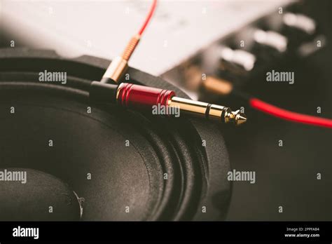 Close Up Red Aux Auxiliary Cable With Male Jack With Speaker In The Background Cable For