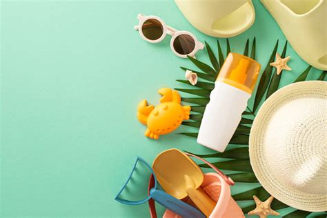 청록색 배경의 야자수 잎에 해양 조개껍데기 해변 장난감 파나마 모자 슬리퍼 선글라스 자외선 차단제를 보여주는 아이들과 함께하는 여름 휴양지의 조감도 텍스트 또는 광고를 위한