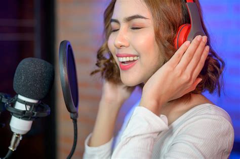 컬러풀한 조명이 달린 음악 스튜디오에서 노래를 녹음하는 동안 마이크가 달린 헤드폰을 착용한 젊은 여성 가수 Popular Music Tour에 대한 스톡 사진 및 기타