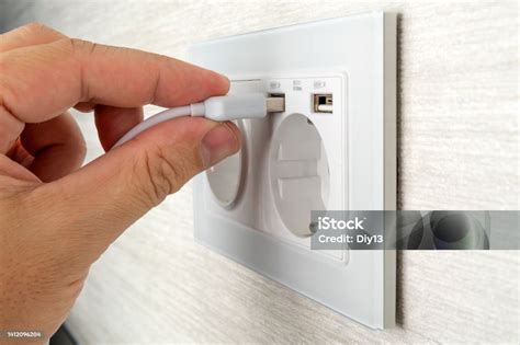 남자는 벽 충전기에 Usb 플러그를 붙든다 유럽 벽면 콘센트 또는 Ac 어댑터가 있는 소켓에 커넥터를 꽂습니다 전원 어댑터에서