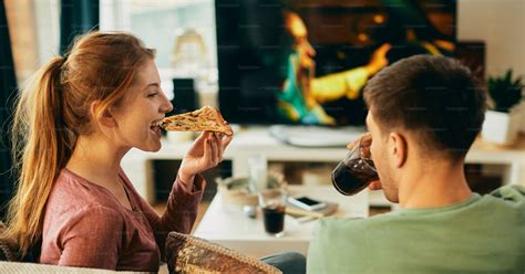 집에서 Tv를 보면서 휴식을 취하는 젊은 부부 초점은 피자를 먹는 여성에 있습니다 사진 Unsplash의 우정 이미지