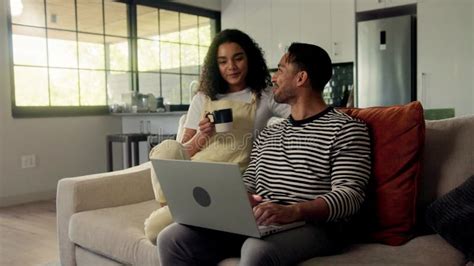 man sitting on couch using laptop computer with thumb on trackpad