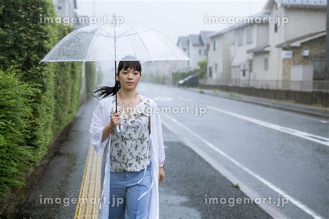 雨の中を傘をさして歩く女性の写真素材 197625364 イメージマート