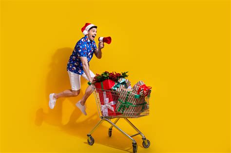 흥분 된 남자 점프 토크 확성기 Xmas 선물 푸시카트 빈 공간 노란색 배경 절연 전체 길이 프로필 사진 산타 클로스에 대한 스톡 사진 및 기타 이미지 Istock