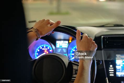 밤에 배경에 흐릿한 도시 가로등으로 스티어링 휠 운전 자동차를 들고 드라이버 손을 닫습니다 계기판 차량 부분에 대한 스톡 사진