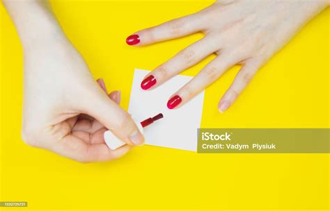 여자는 노란색 배경에 빨간색 매니큐어를 적용합니다 매니큐어를 만드는 소녀 집에서 살롱 절차 아름다운 손과 손톱 클로즈업 매크로 사진 화려하고 창조적인 개념에 대한 스톡 사진