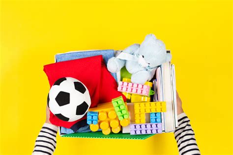 기부 개념 노란 배경에 옷 책 장난감으로 기부 상자를 들고 있는 여자 손 위쪽 보기 Charitable Foundation에 대한 스톡 사진 및 기타 이미지