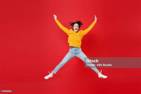 밝은 빨간색 배경 스튜디오 초상화에 고립 된 손을 열고 손을 열고 입을 유지 기본 노란색 스웨터 점프에 흥분 의 전체 길이 는 쾌활한 젊은 갈색 머리 여성 20 S 여자에
