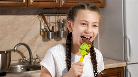 Teen Girl Licks Plastic Spatula With Chocolate And Smiling Stock Image
