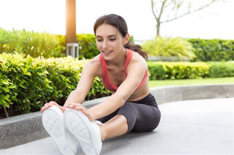 스포츠 소녀는 미소 얼굴로 운동하기 전에 손을 만지는 신발을 사용하여 다리를 스트레칭합니다 운동이나 조깅 전에 아름다운 여성 워밍업 몸 다리 햄스트링 스트레칭 스포츠 및