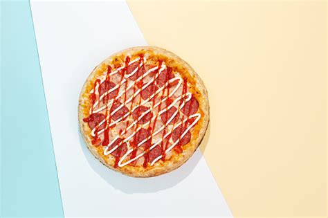 색깔이있는 배경에 햄과 살라미가있는 이탈리아 피자 햄 케첩 및 마요네즈가 들어간 고기 피자는 파란색으로 최소한의 스타일로 제공됩니다 컬러 배경을 가진 미국 피자 배달 개념