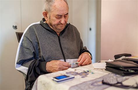 당뇨병을 앓고 있는 삶 78세의 한 노인이 집에서 혈액의 포도당 수준을 확인합니다 그는 검사를 위해 혈액 투하를 취할 랜싯을 준비하고 있다 70 79세에 대한 스톡 사진 및