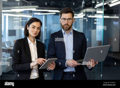 Business Professionals In Formal Attire Engage With Digital Devices In Modern Office Environment