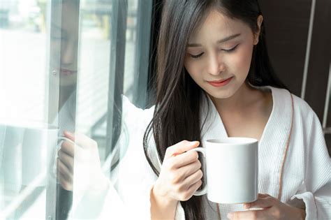 호텔 방에서 창문 옆에 서있는 커피 한 잔을 들고 있는 젊은 아시아 여성 25 29세에 대한 스톡 사진 및 기타 이미지 25 29세 동남아시아 민족 마시기 Istock