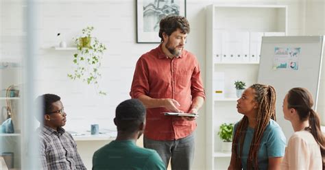 사무실에서 비즈니스 프로젝트에 대해 논의하는 동안 동그라미에 앉아 있는 다민족 그룹의 사람들 동료들과 이야기하는 웃는 수줍은 관리자에 초점을 맞추고 공간을 복사합니다