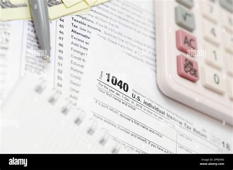 The Pen Notebook Calculator And Dollar Bills Is Lies On The Tax Form