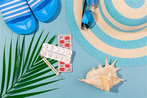 줄무늬 모자 선글라스 파란색 플립 플롭 야자수 잎 조개 흰색과 빨간색 발열 알약과 민트 녹색 배경에 온도계에 상단보기 바다에서 휴가에 질병을 준비하는 개념 광고 공간 해변에