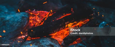 불에 타버린 생생한 연기가 나는 장작이 클로즈업되었습니다 모닥불의 주황색 불꽃이 있는 분위기 있는 배경 공중에서 빛나는 불씨가 있는 모닥불의 멋진 풀 프레임 이미지 따뜻한