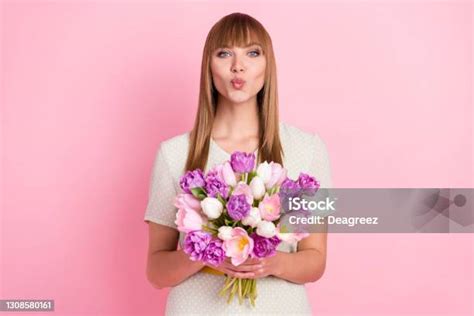 손에 들고 매력적인 소녀의 초상화 꽃 핑크 파스텔 색상 배경에 고립 된 공기 키스를 보내는 축하 금발 머리에 대한 스톡 사진 및