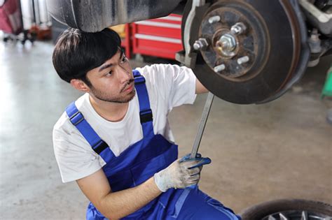 남자 기술자 자동차 정비사는 제복을 입고 수리 차고 역에서 리프트 자동차 서비스를 점검하거나 유지 보수합니다 렌치를 잡고 브레이크 디스크를 고정하는 작업자 자동차 센터 수리