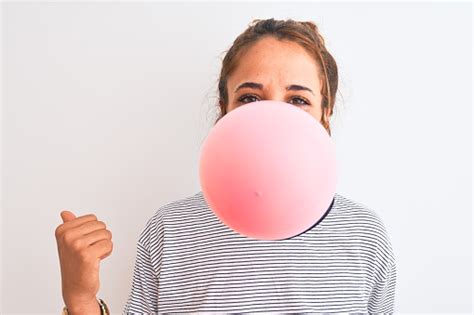 젊은 빨간 머리 여자 껌을 츄고 머리 거품을 부는 흰색 고립 된 배경 가리키는 하 고 행복 한 얼굴 미소와 함께 측면에 엄지 손가락으로 표시 기포에 대한 스톡 사진 및 기타