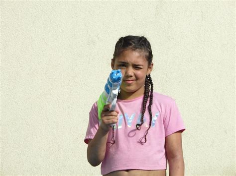 Premium Photo Portrait Of Girl Holding Squirt Gun Standing Against Wall