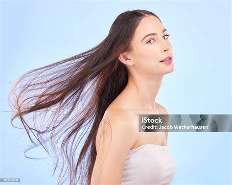 초상화 머리카락 바람은 스킨케어 또는 각질 치료를 위해 파란색 배경에 스튜디오에서 모델 여성과 함께 합니다 스파 미용실 미용실 미용실 미용 또는 샴푸 홍보를 위해 포즈를