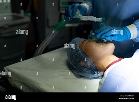 Hands Of Surgical Tech Giving Gas To Asian Female Patient On Operating Table In Theatre Stock