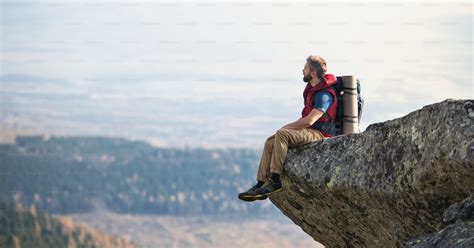 가을에 산에서 배낭 하이킹을 하고 바위 위에서 쉬고 있는 성숙한 남자 공간을 복사합니다 사진 Unsplash의 자연 이미지