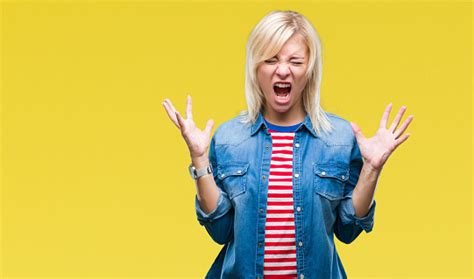 이상의 데님 자 켓을 입고 젊은 아름 다운 금발의 여 자가 고립 배경 화가 미친 비명 제기 및 닫힌 눈 흥분 하는 무기와 성공을